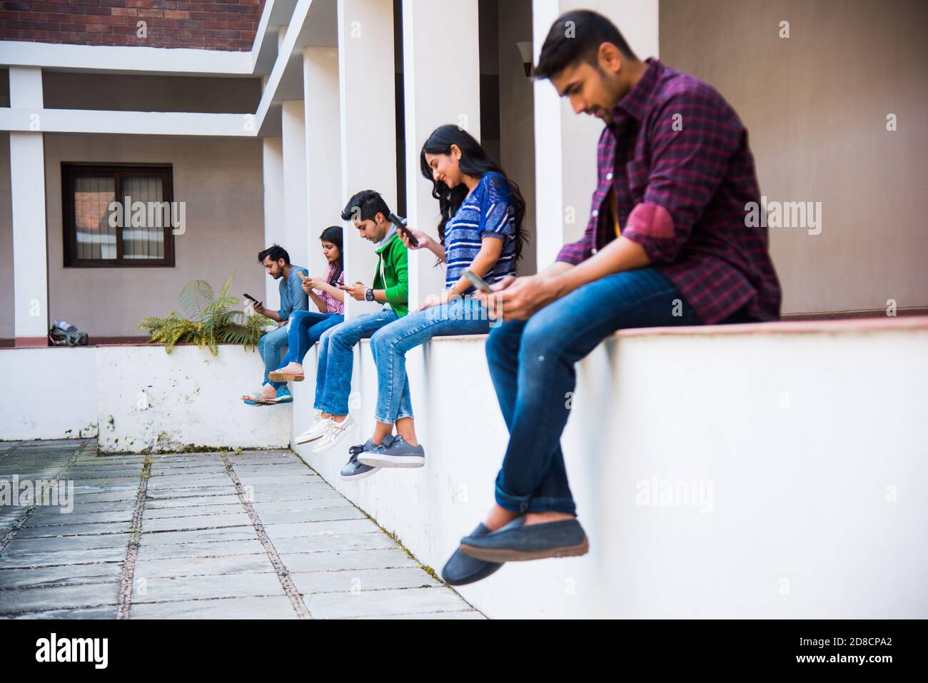 Asian Indian college students using smartphone while sitting in college ...