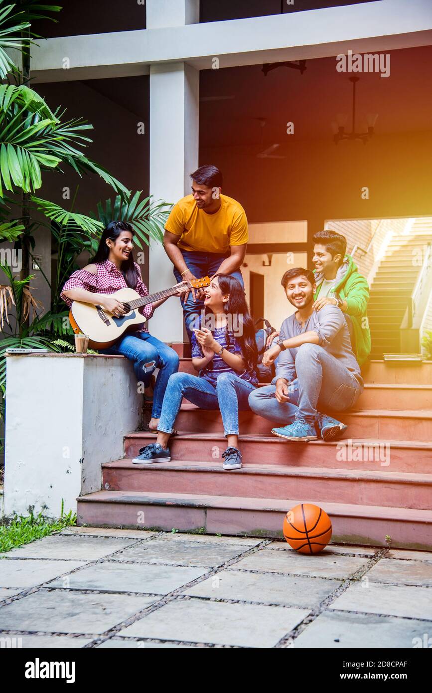 Asian Indian college students playing music with guitar while sitting ...