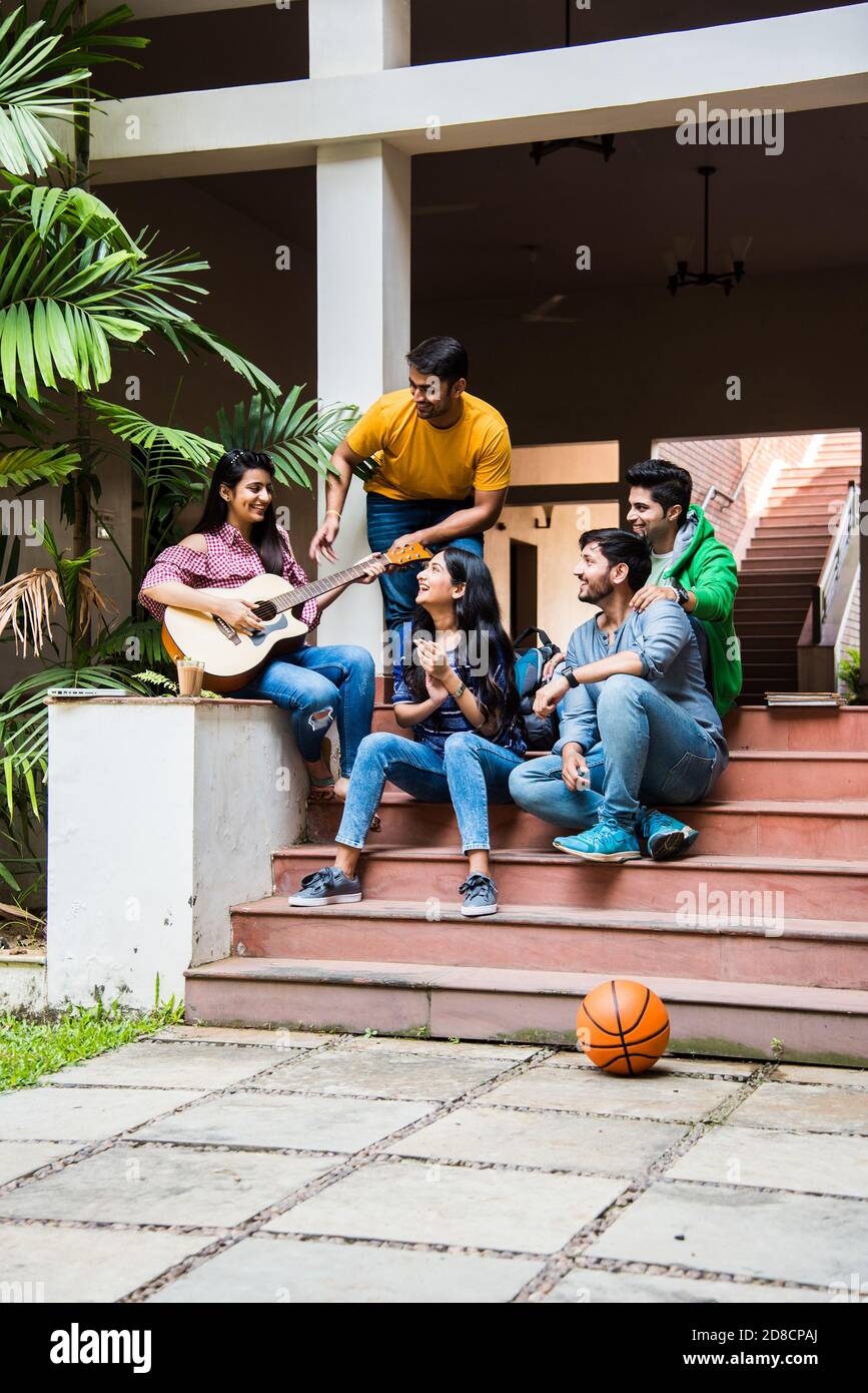 Asian Indian college students playing music with guitar while sitting ...