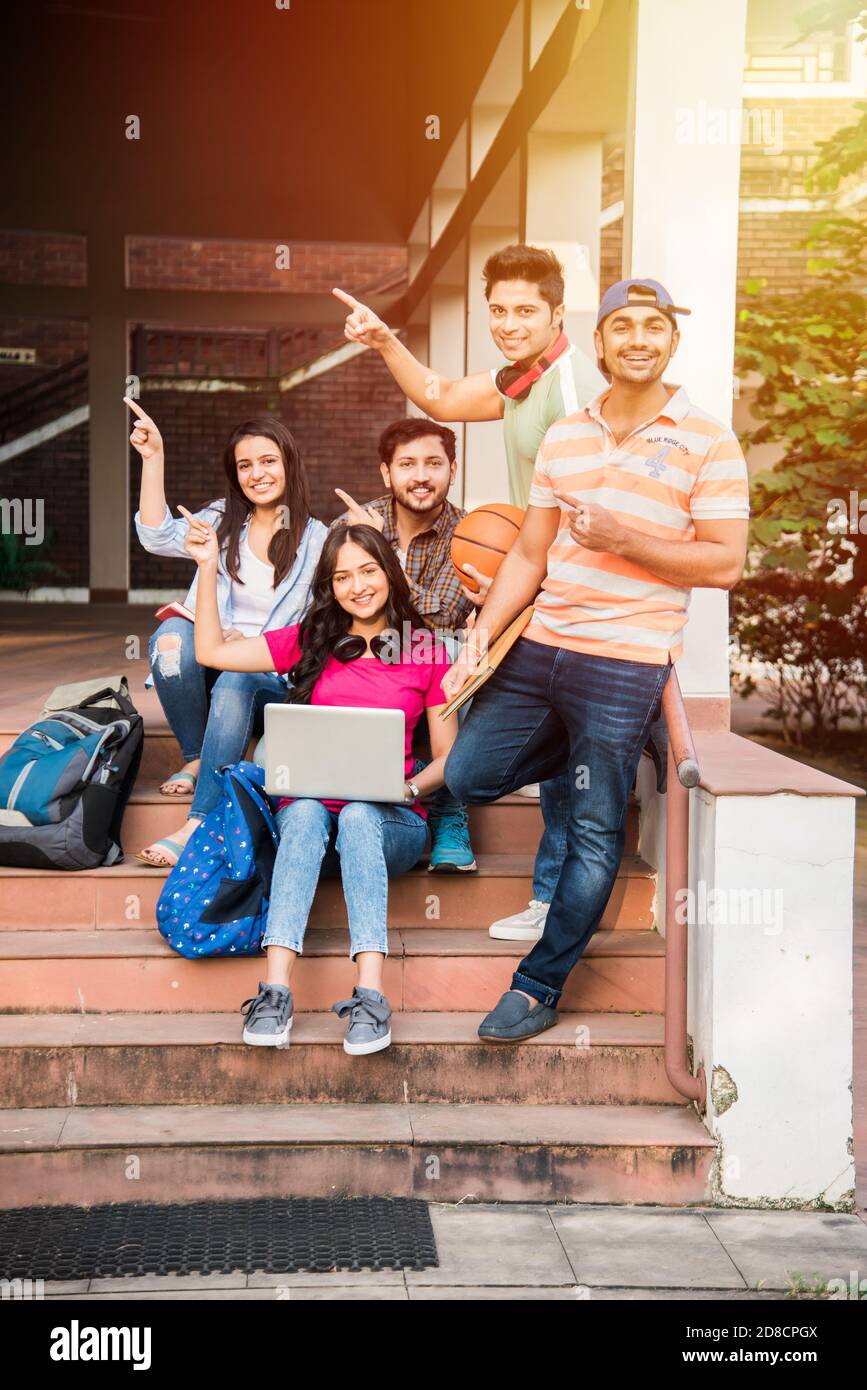 Cheerful group of Indian asian college students pointing at blank while ...