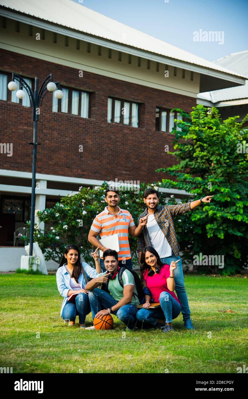 Cheerful group of Indian asian college students pointing at blank while ...