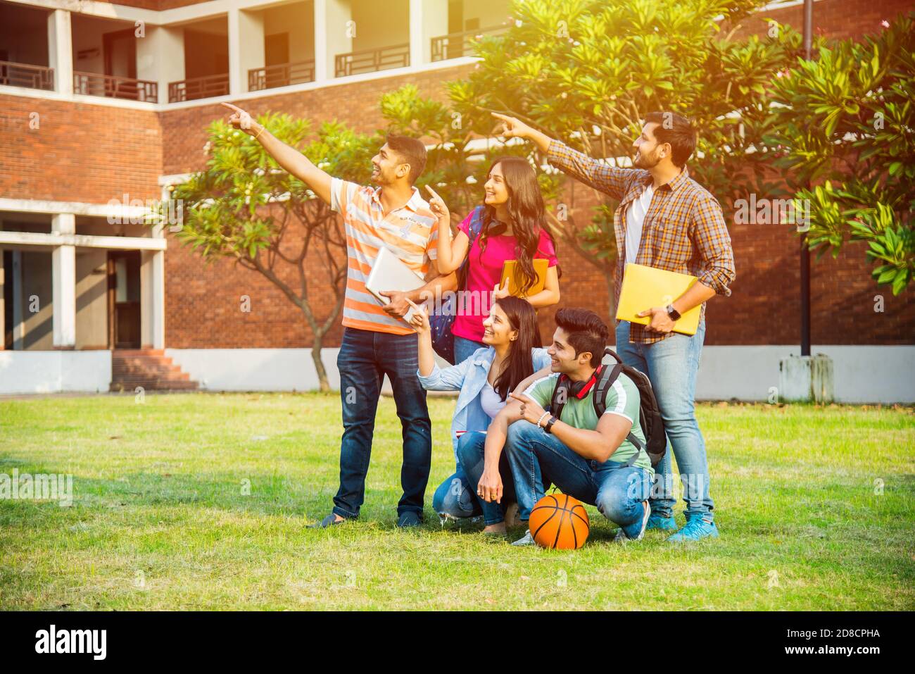 Cheerful group of Indian asian college students pointing at blank while ...