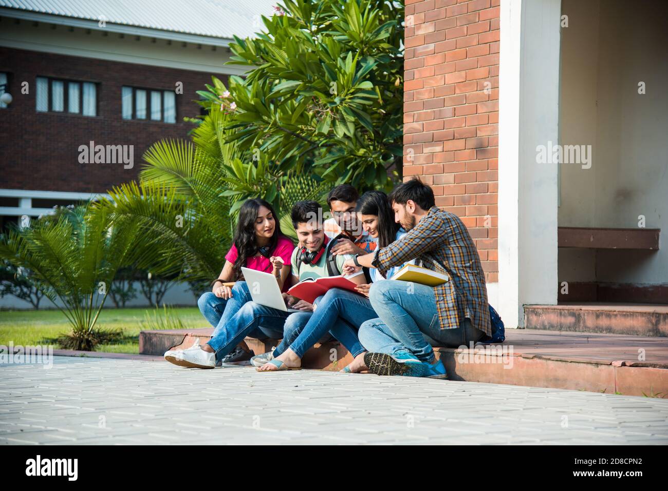 Young Asian Indian college students reading books, studying on laptop ...