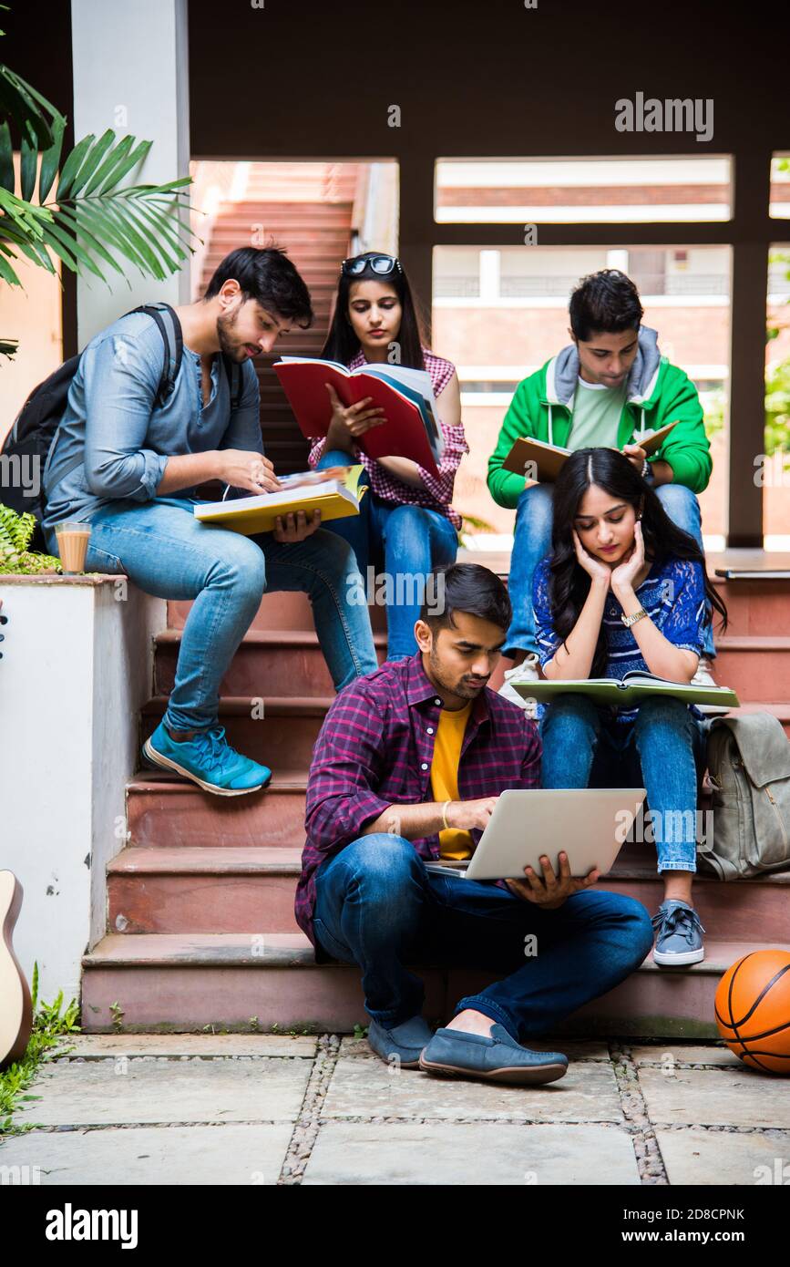 Young Asian Indian college students reading books, studying on laptop ...