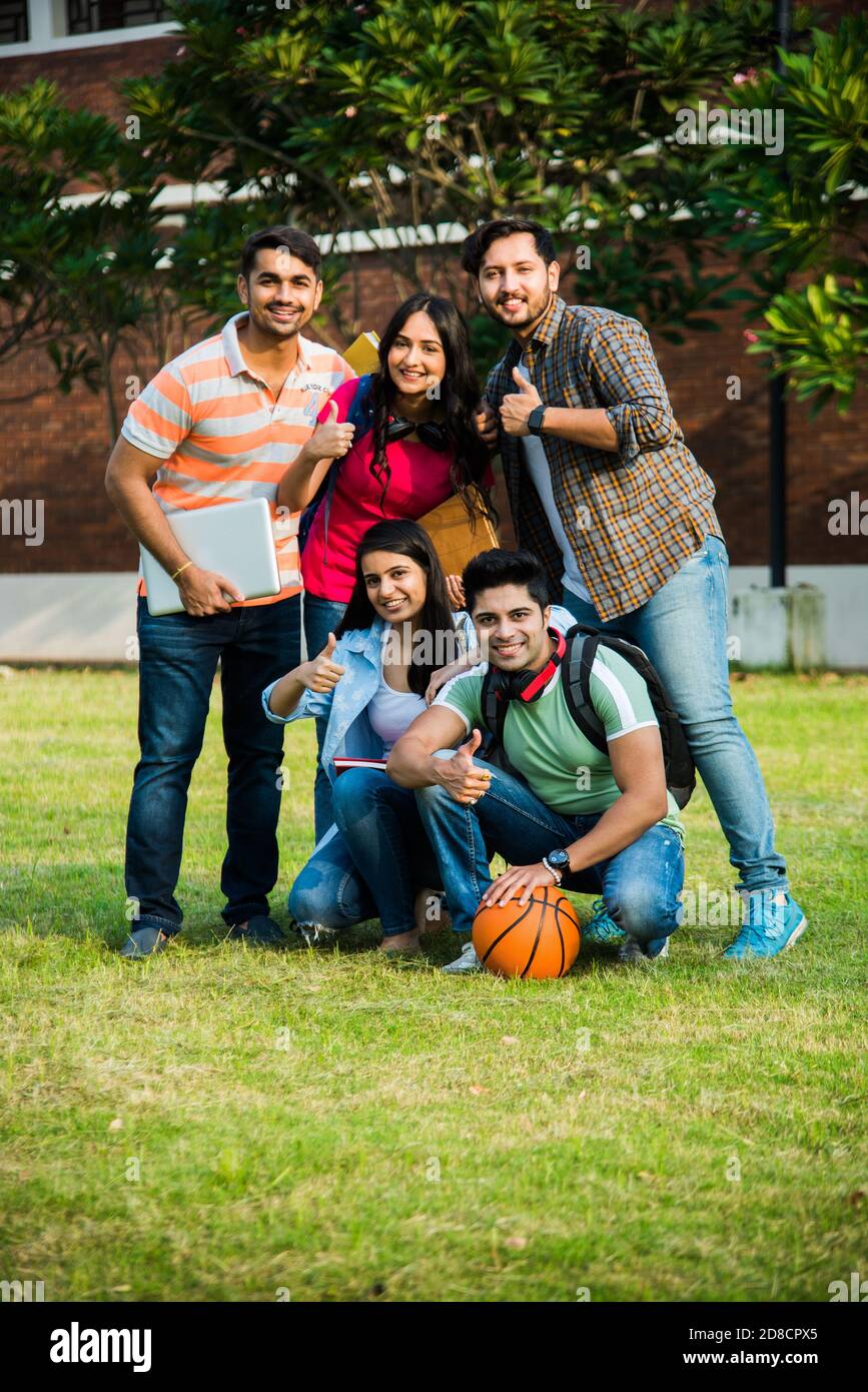Cheerful group of Indian asian college students pointing at blank while ...