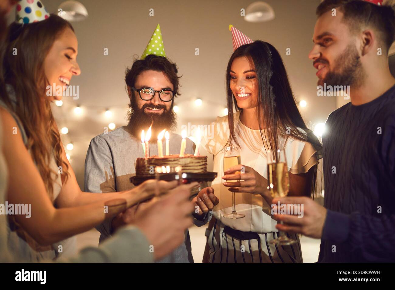 Smiling friends celebrating birthday and having party with holiday cake ...