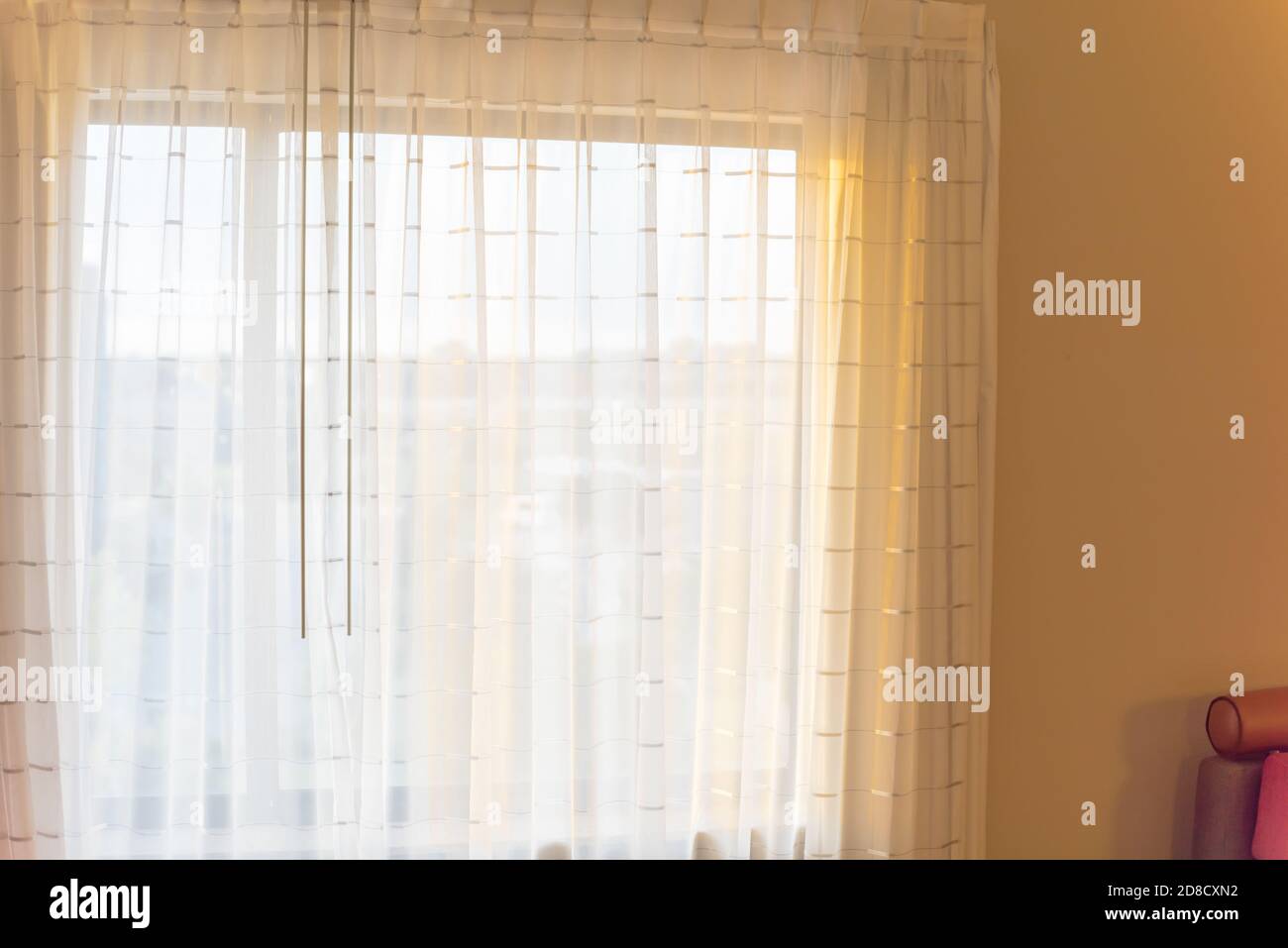 Hotel room with white curtain, drapery baton and backlit morning light ...