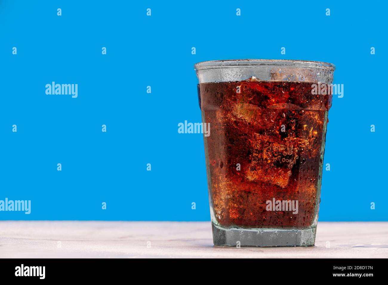 Ice cold glass of soda, fizzy drink, pop on a blue background with ...