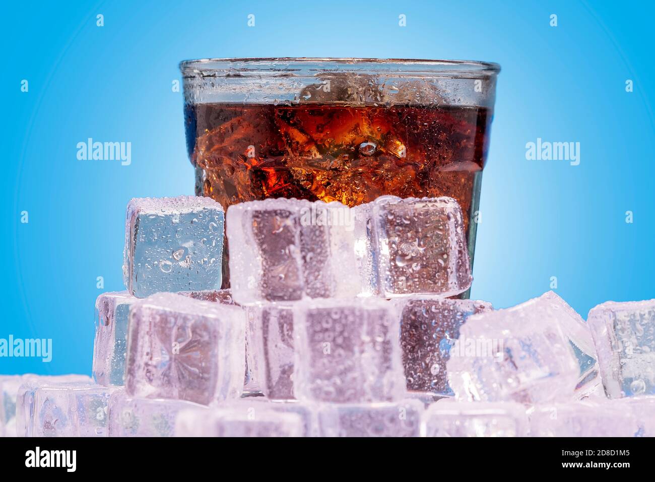 Ice cold glass of cola, soda, fizzy drink pop surrounded by ice cubes with condensation on a ...