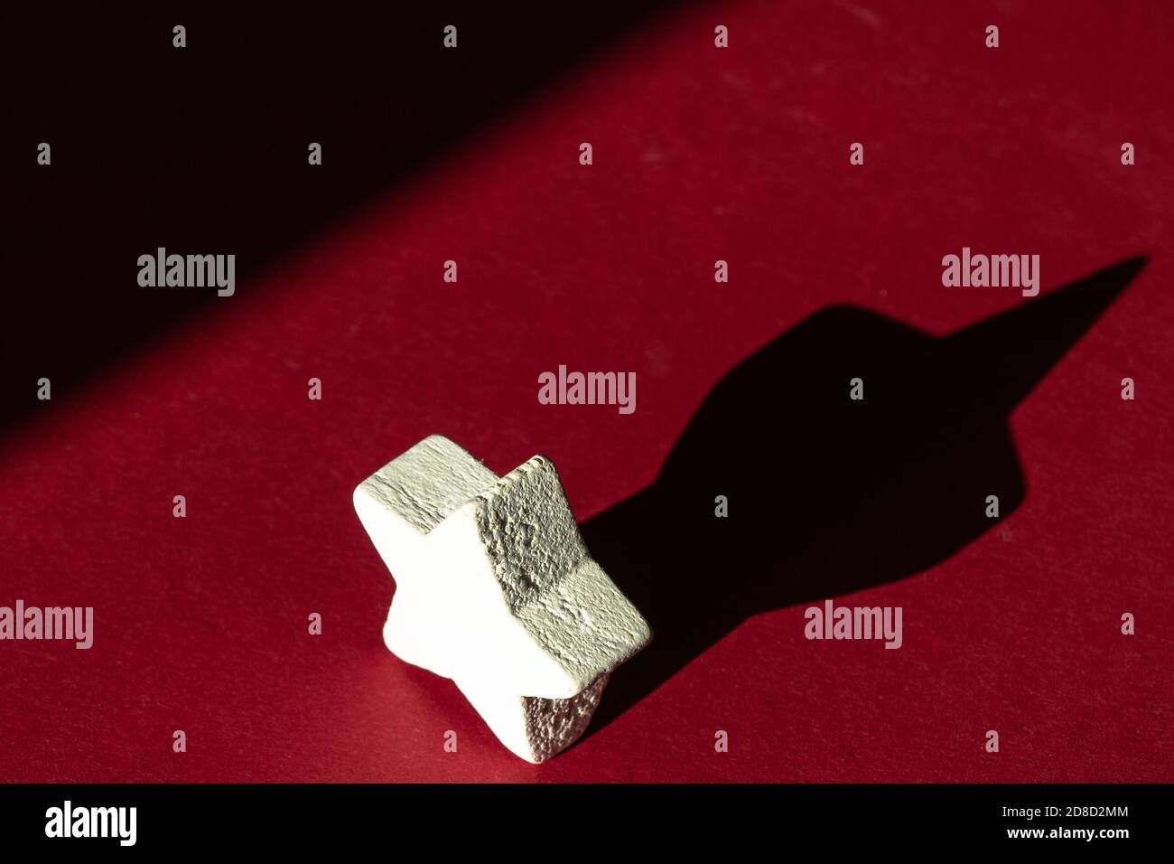 Single white, textured wooden star with a sharp shadow, against a ...