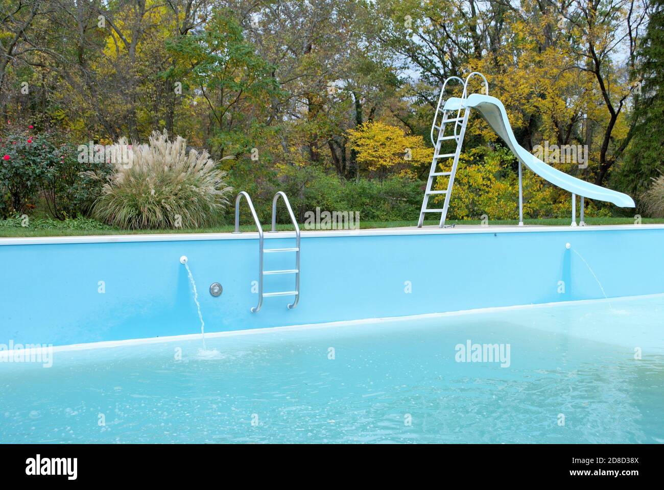 backyard swimming pool with pool slide and ladder emptied out shutting ...