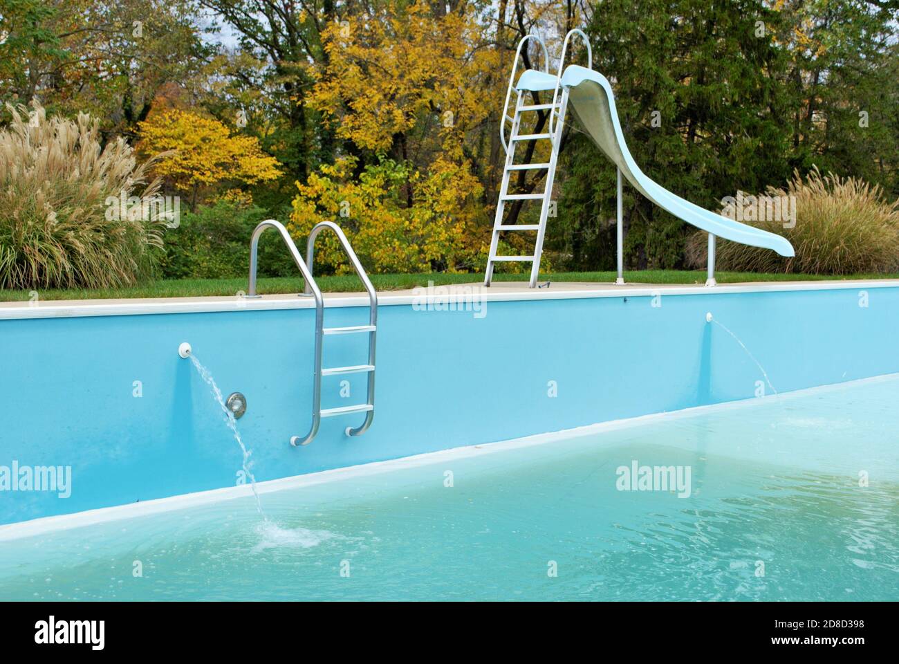 backyard swimming pool with pool slide and ladder emptied out shutting ...