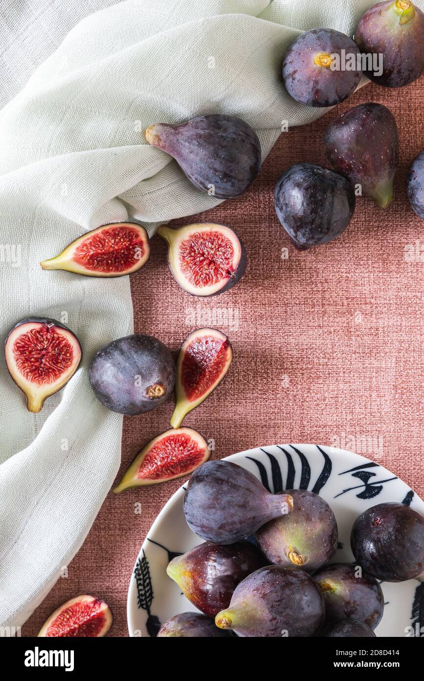 fresh cut and whole figs on a plate and pink textured background, light ...