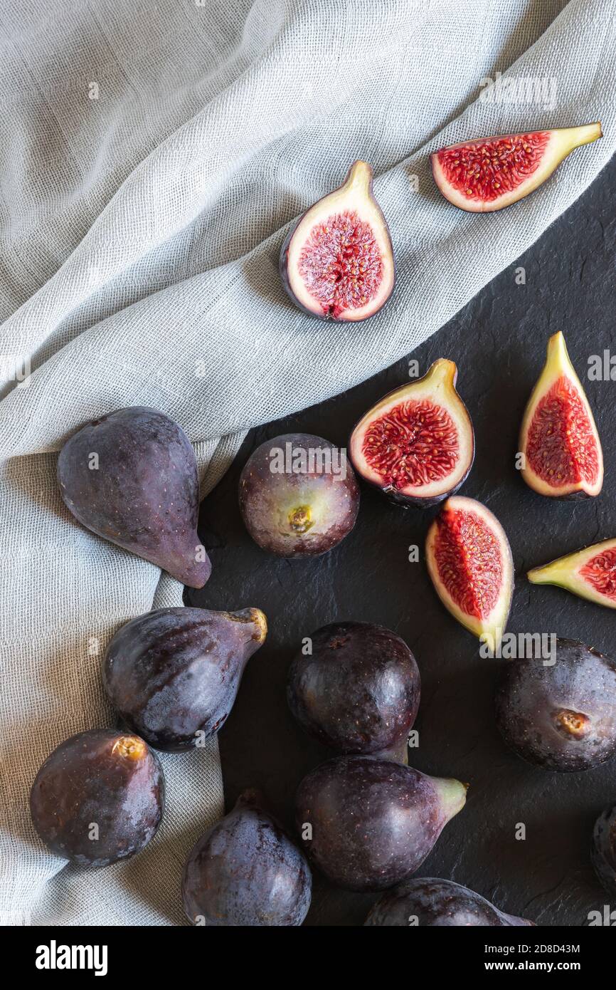 fresh cut and whole figs arranged on black background and light linen ...
