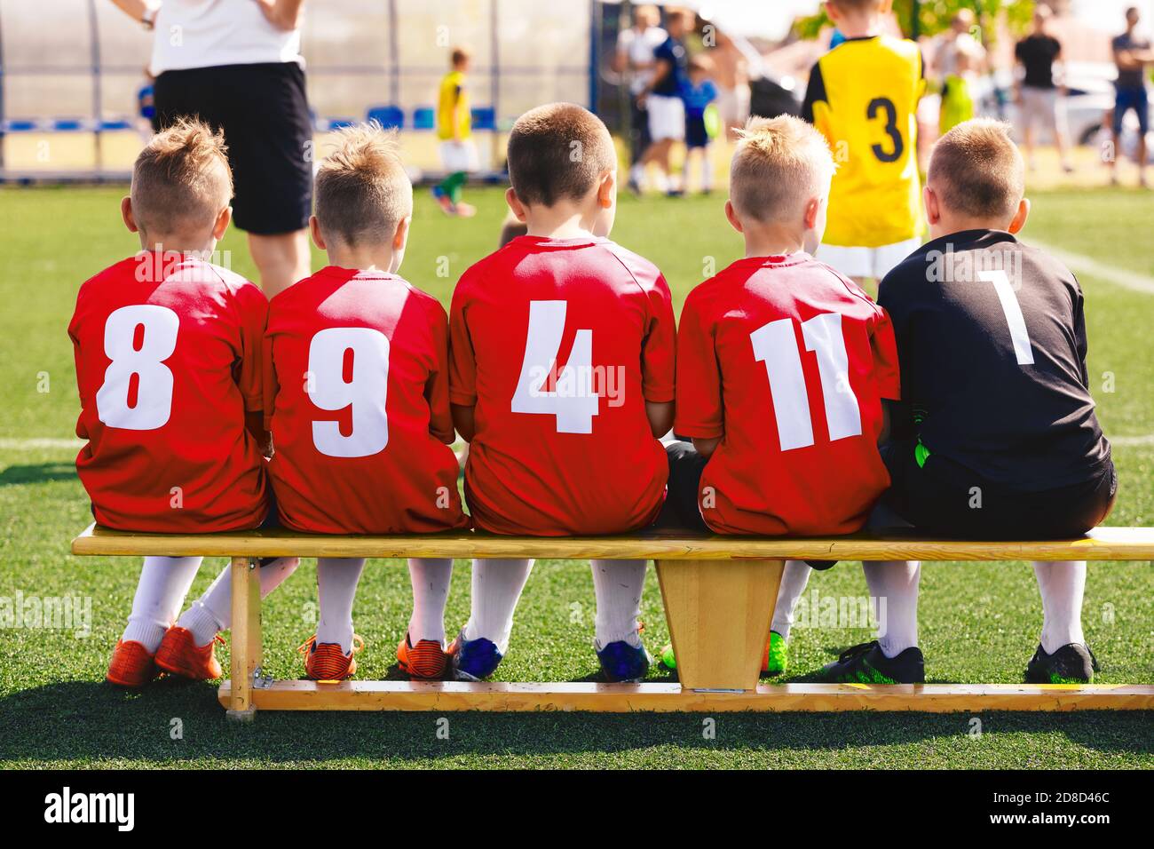 Boys in red shirt sports team. Children sitting on substitute soccer ...