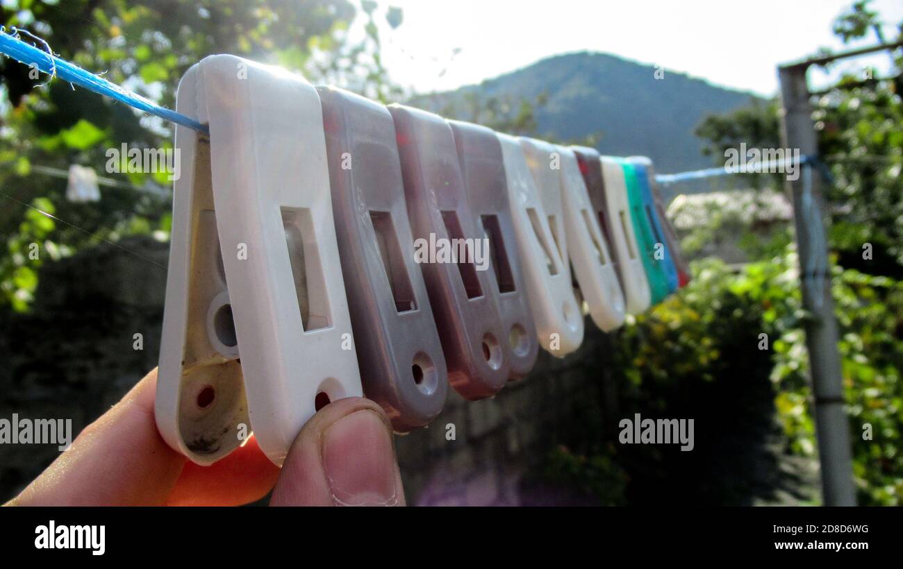 A close up of a male hand holding clothes pins on a clothes line rope ...