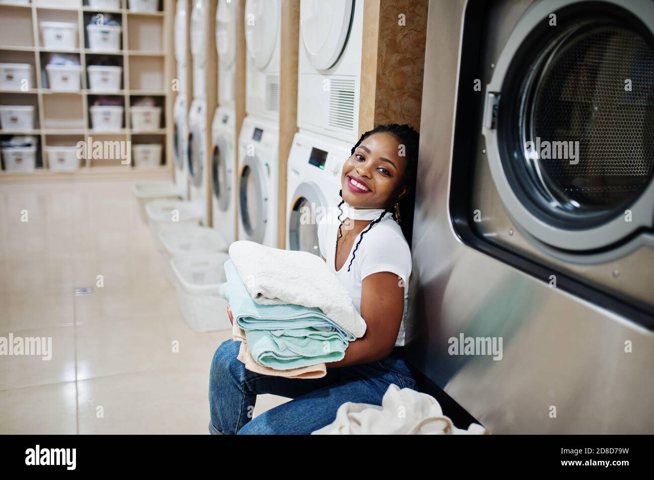 Cheerful african american woman with towels in hands near washing ...