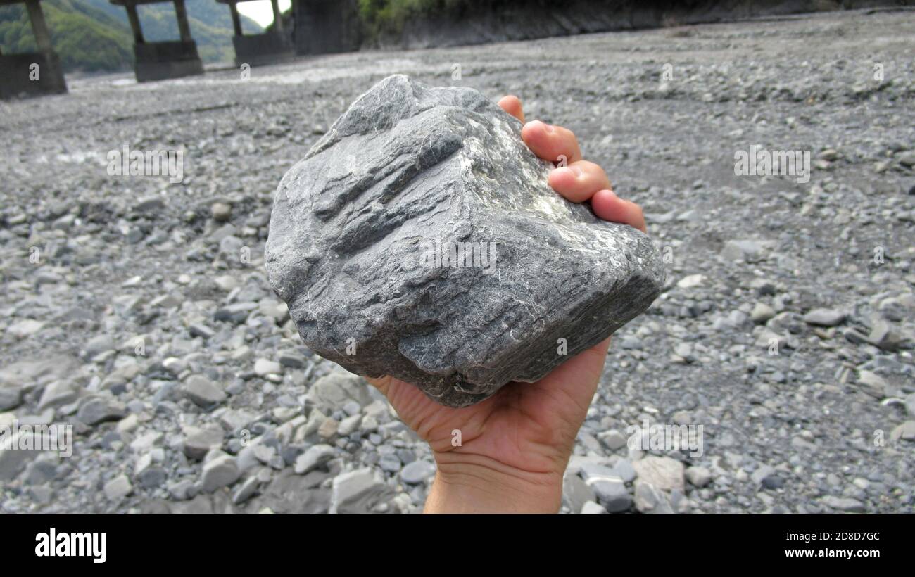 Close up of young male hand holding a natural river stone in his hand ...