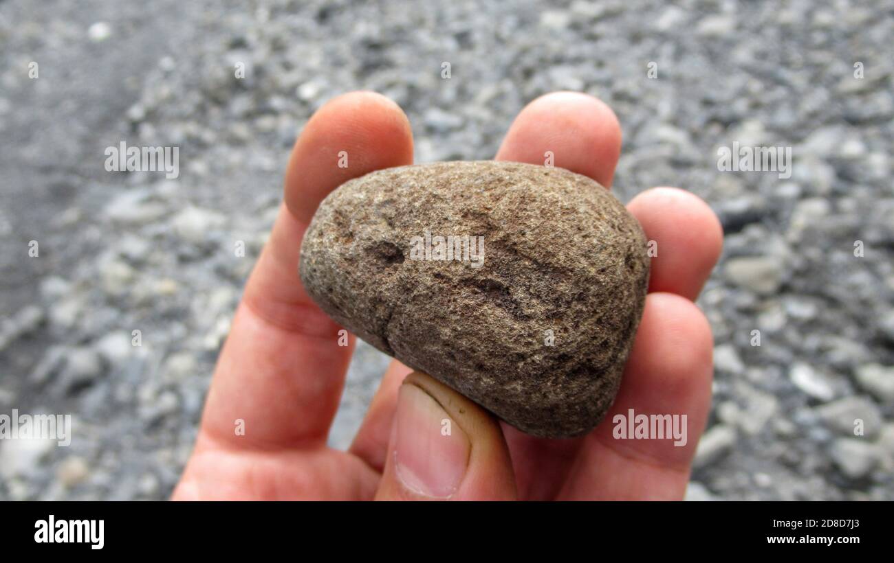 Close up of young male hand holding a natural river stone in his hand ...