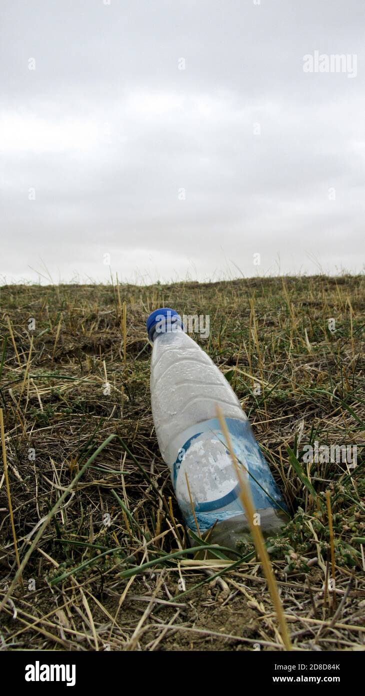 Single plastic bottle waste on the green grass and soil Stock Photo - Alamy