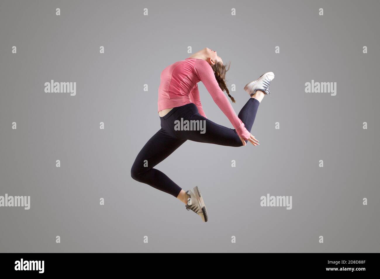 Portrait of modern female dancer jumping in the air by gray wall Stock ...