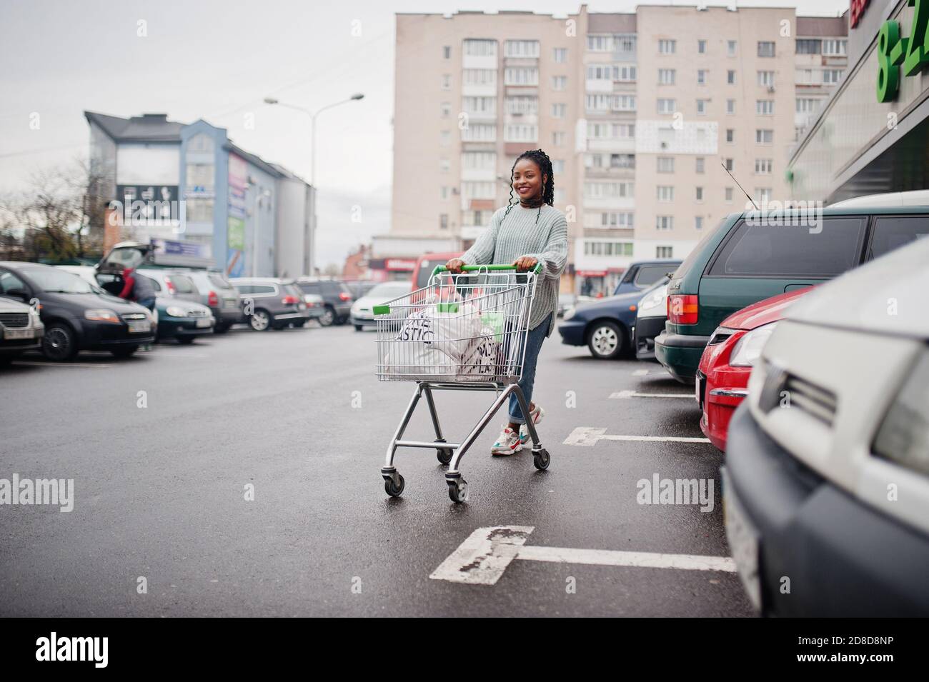 African woman with shopping cart trolley posed outdoor market near car ...