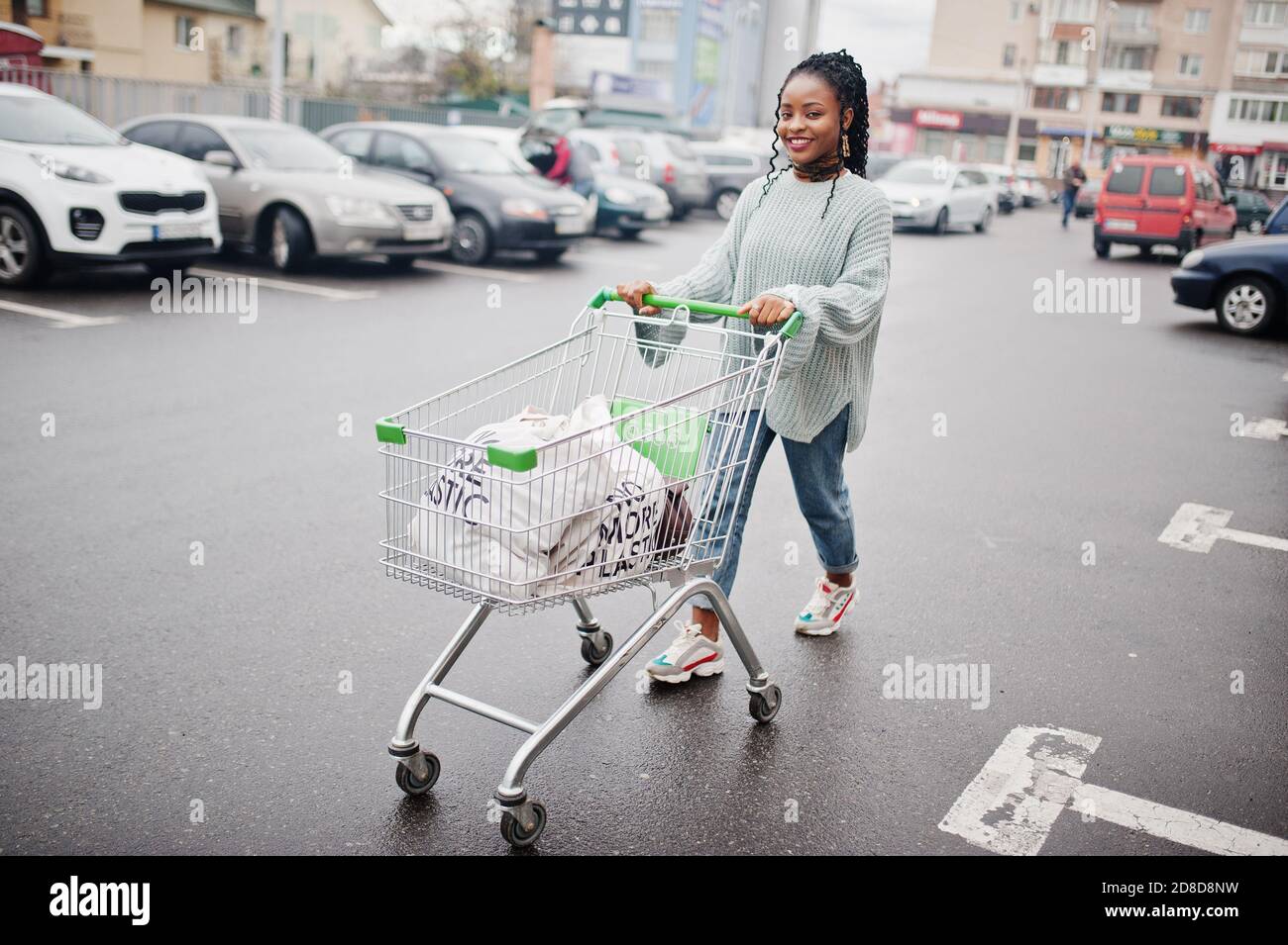 African woman with shopping cart trolley posed outdoor market near car ...