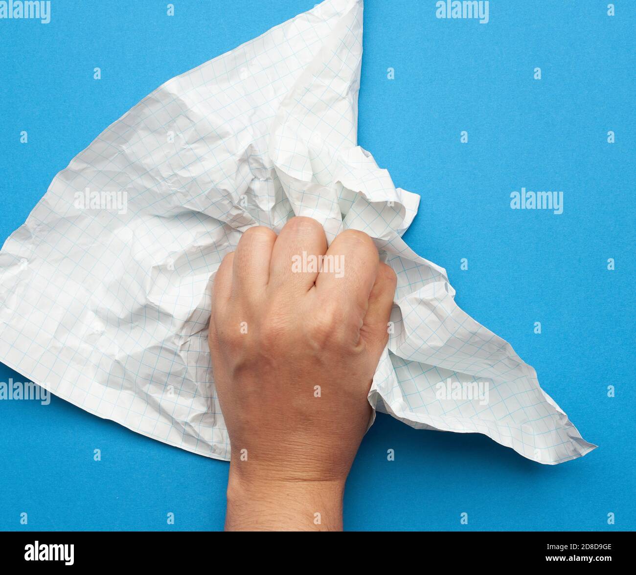 woman holds in her hand a crumpled sheet of paper in a cage on a blue ...