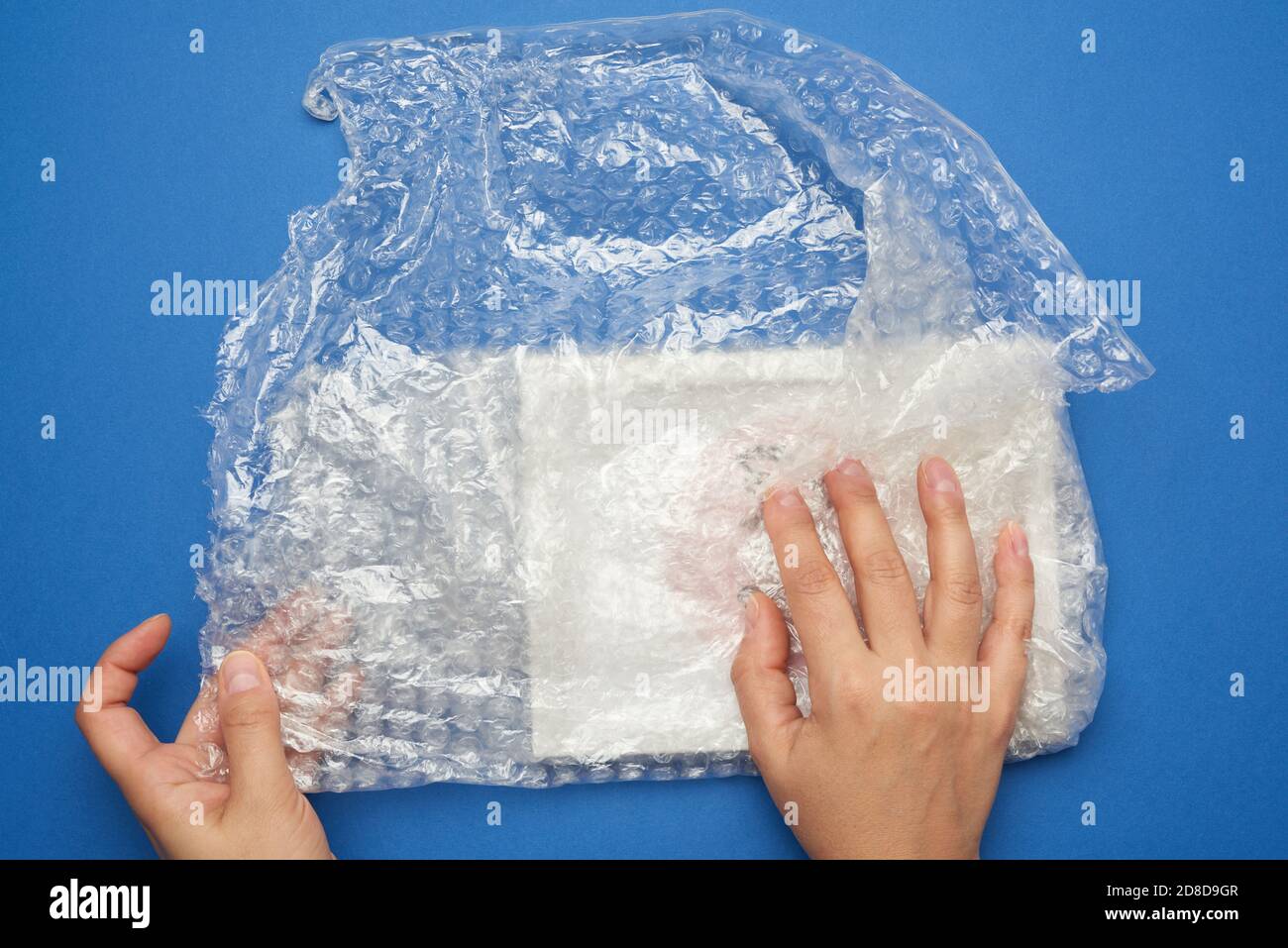 two female hands are wrapping the item in a transparent plastic wrap ...