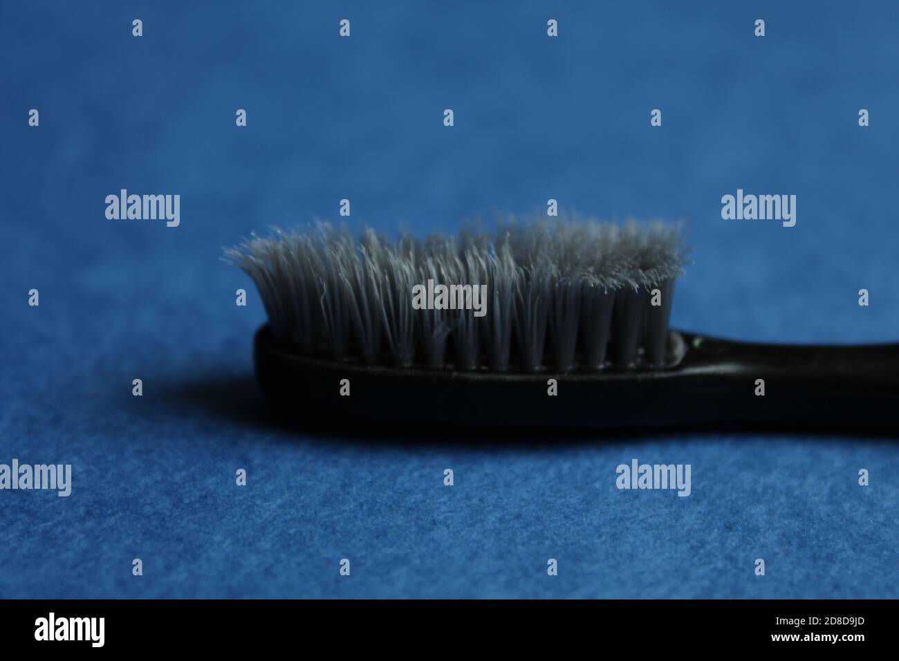 black gray old used toothbrush on a blue background side view of copy ...