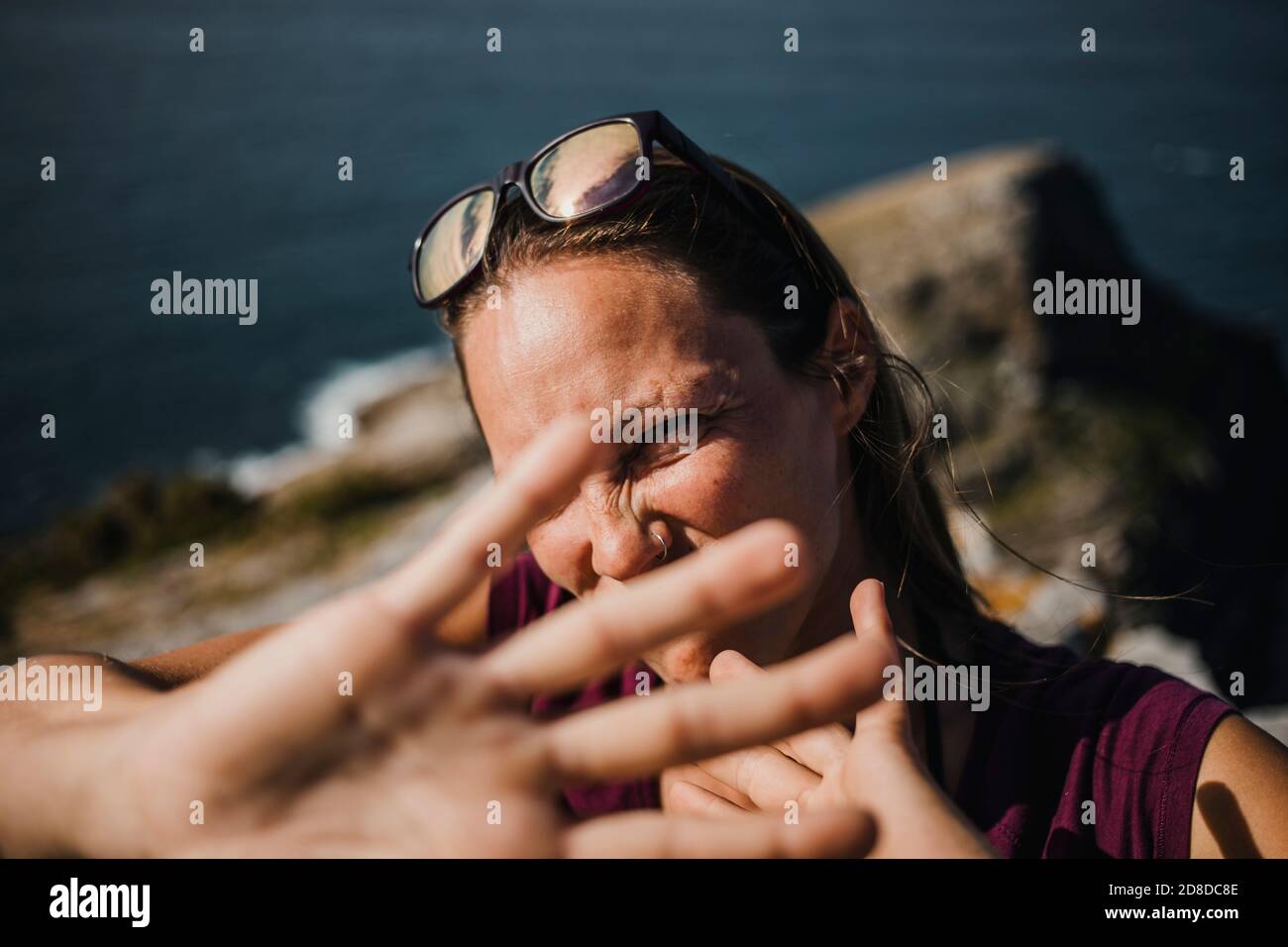 Playful woman trying to hide from photographer camera to avoid pics ...