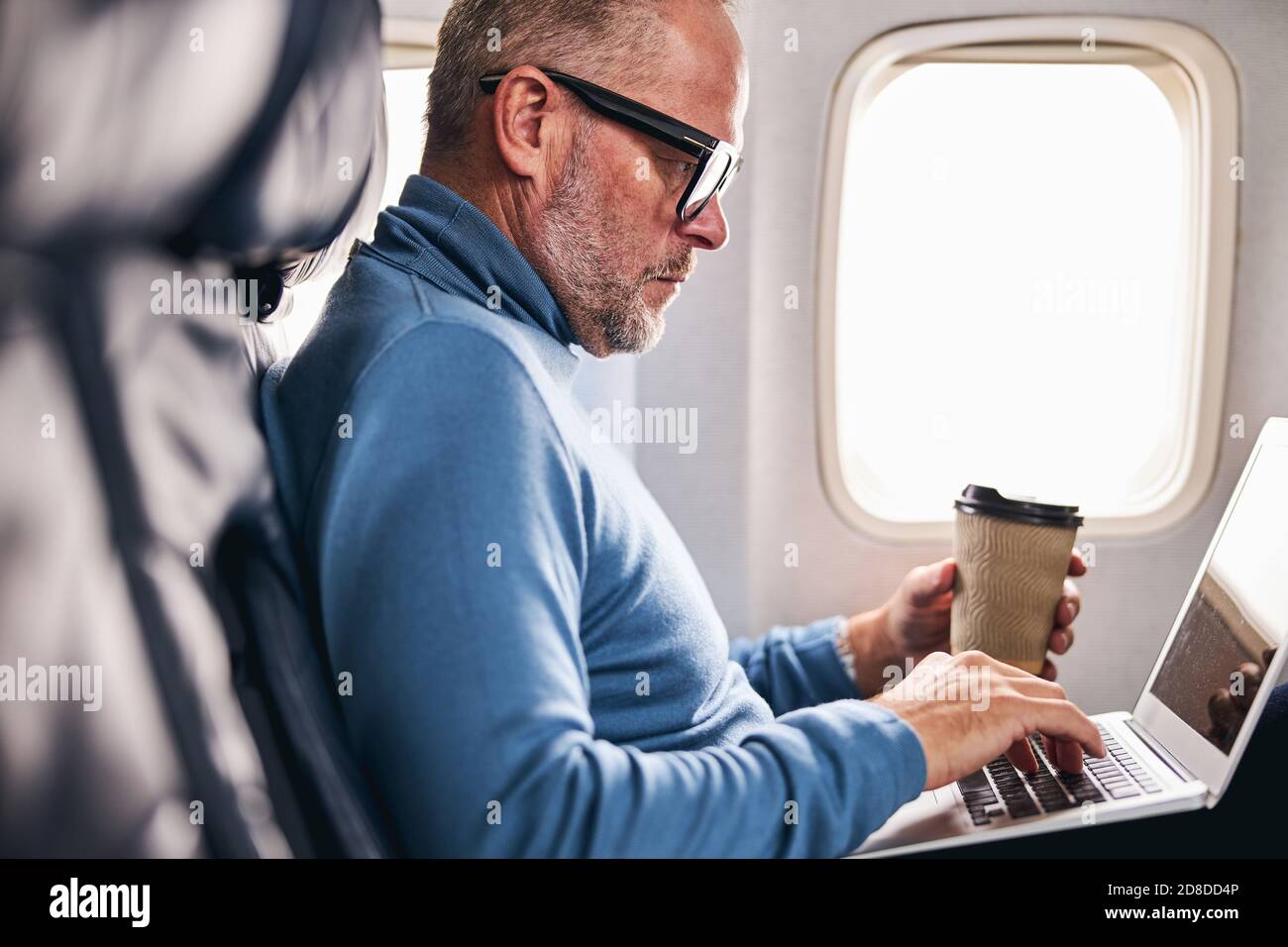 Airline passenger using his computer for work Stock Photo - Alamy
