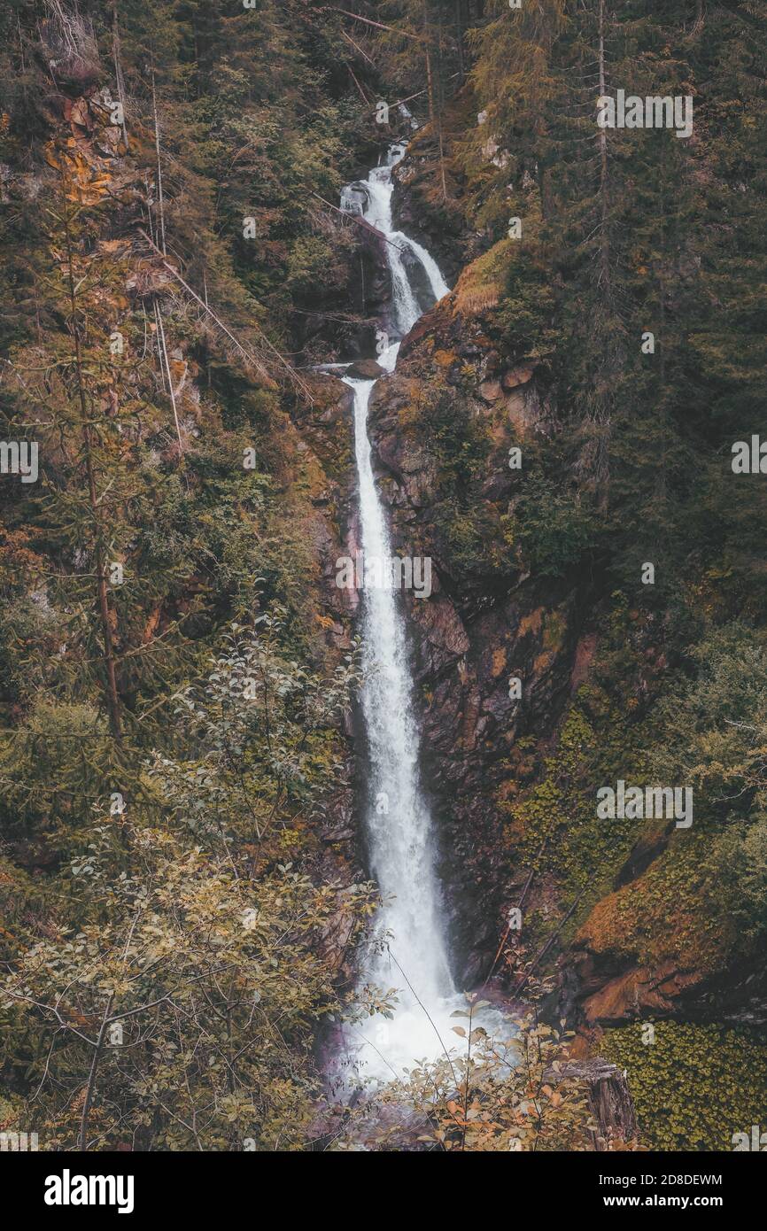 Majestic vertical shot of a tall long waterfall flowing over a rocky ...