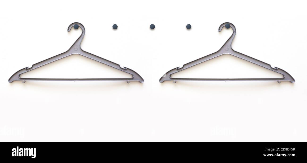 Two white wooden hanger without clothes on background of white wall ...
