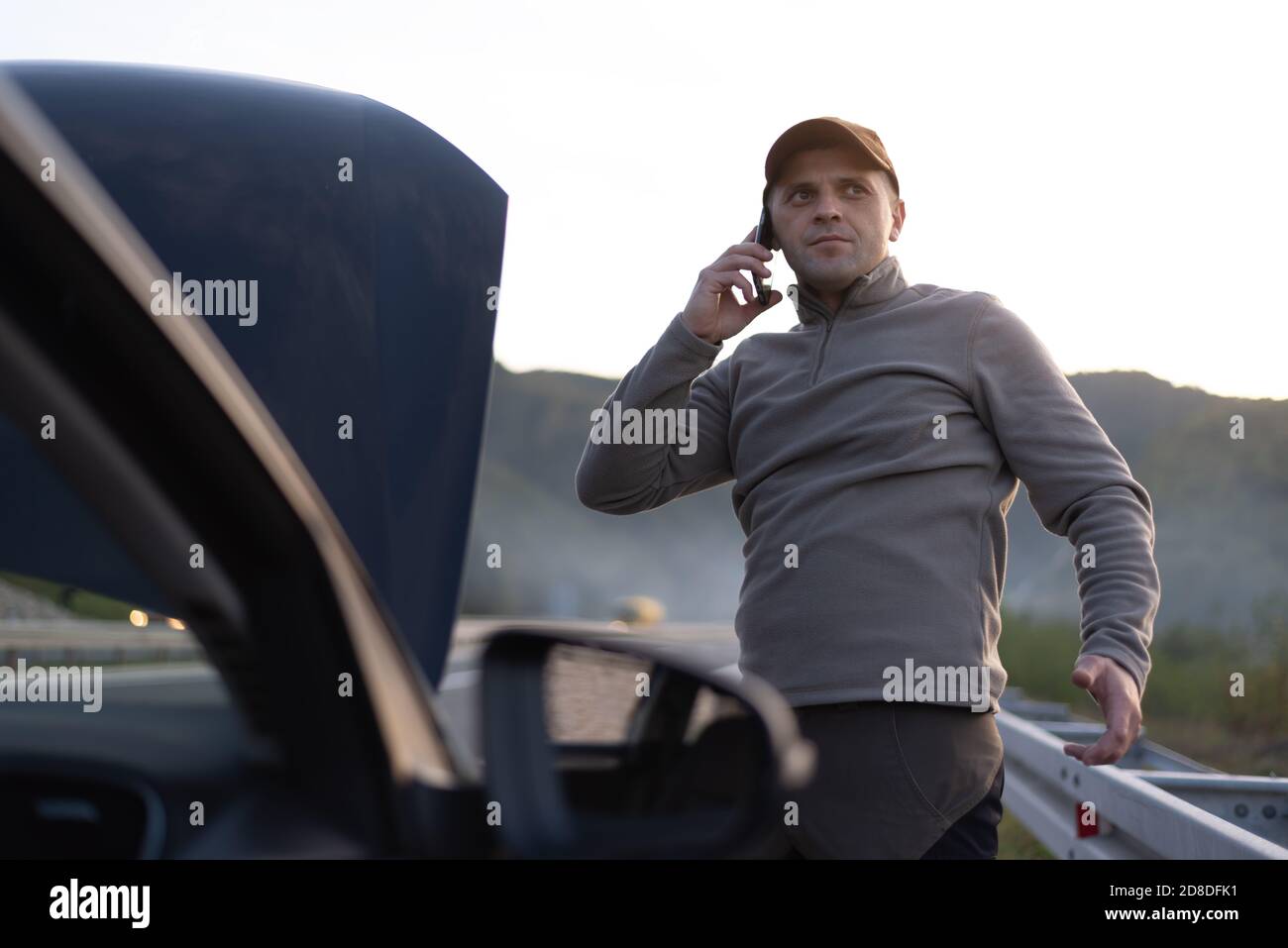 Frustrated and angry man calls roadside assistance by phone. car problem. Roadside assistance ...