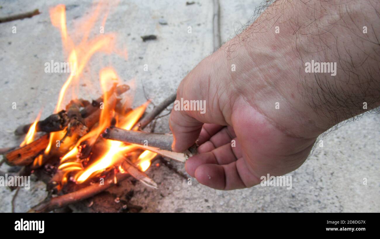 Male hand puting small wooden on to fire Stock Photo - Alamy