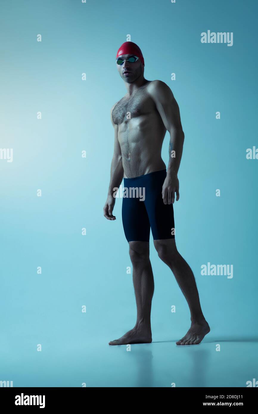 Professional caucasian male swimmer with hat and goggles practicing and ...