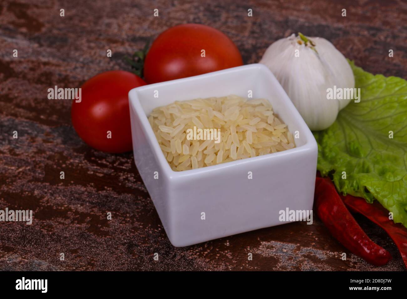 Raw uncooked rice in the bowl served pepper and salad leaves Stock ...