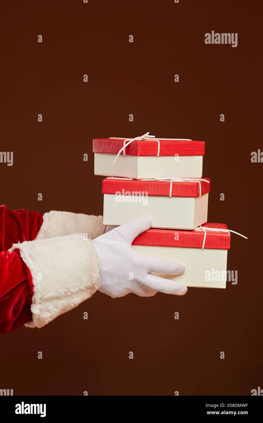Close-up of Santa Claus in gloves holding stack of Christmas presents ...