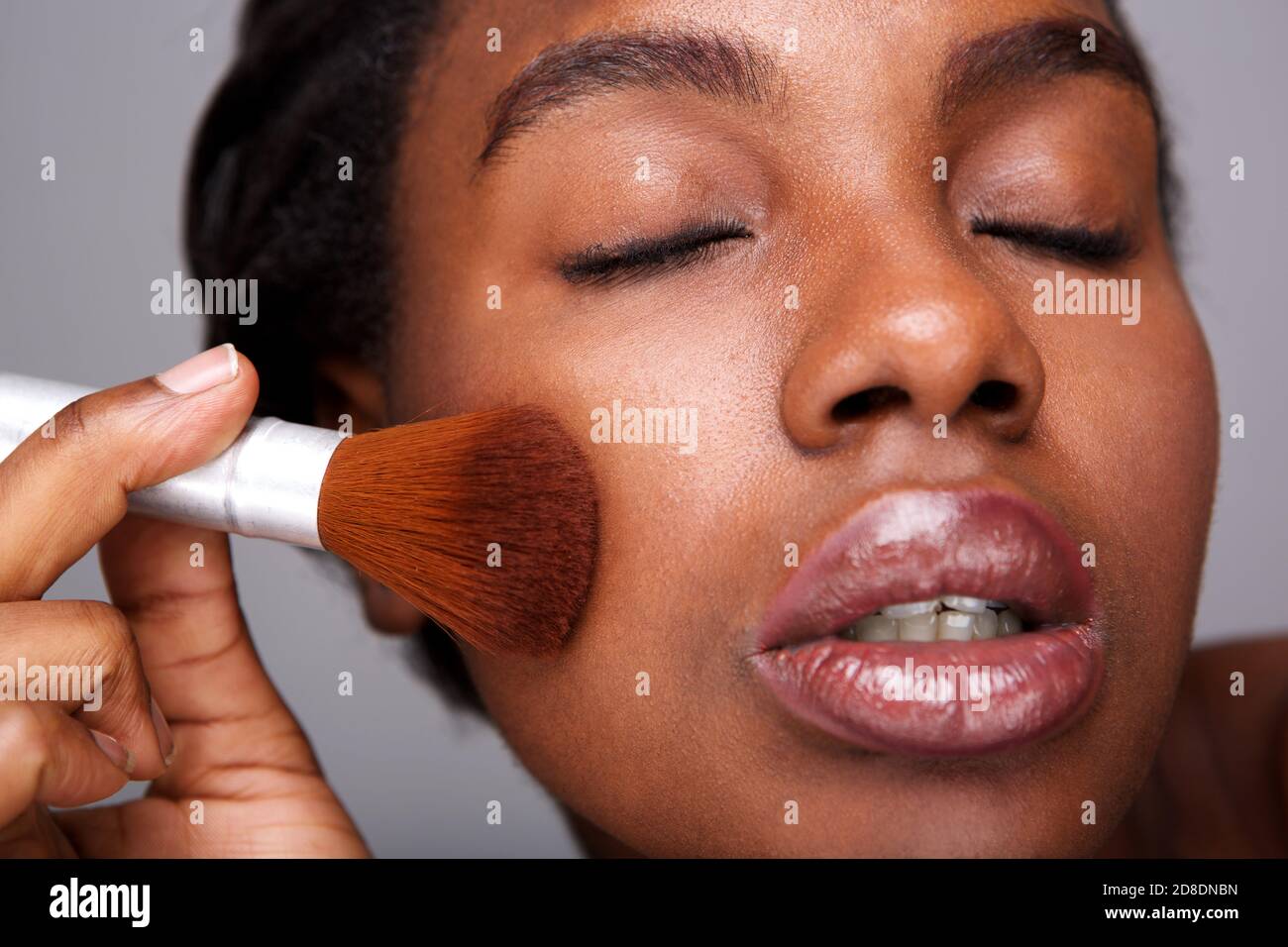 Close up portrait of attractive woman applying makeup with brush for ...