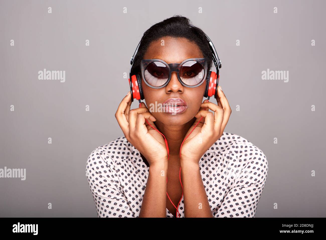 Close up portrait of serious woman with sunglasses listening to music ...