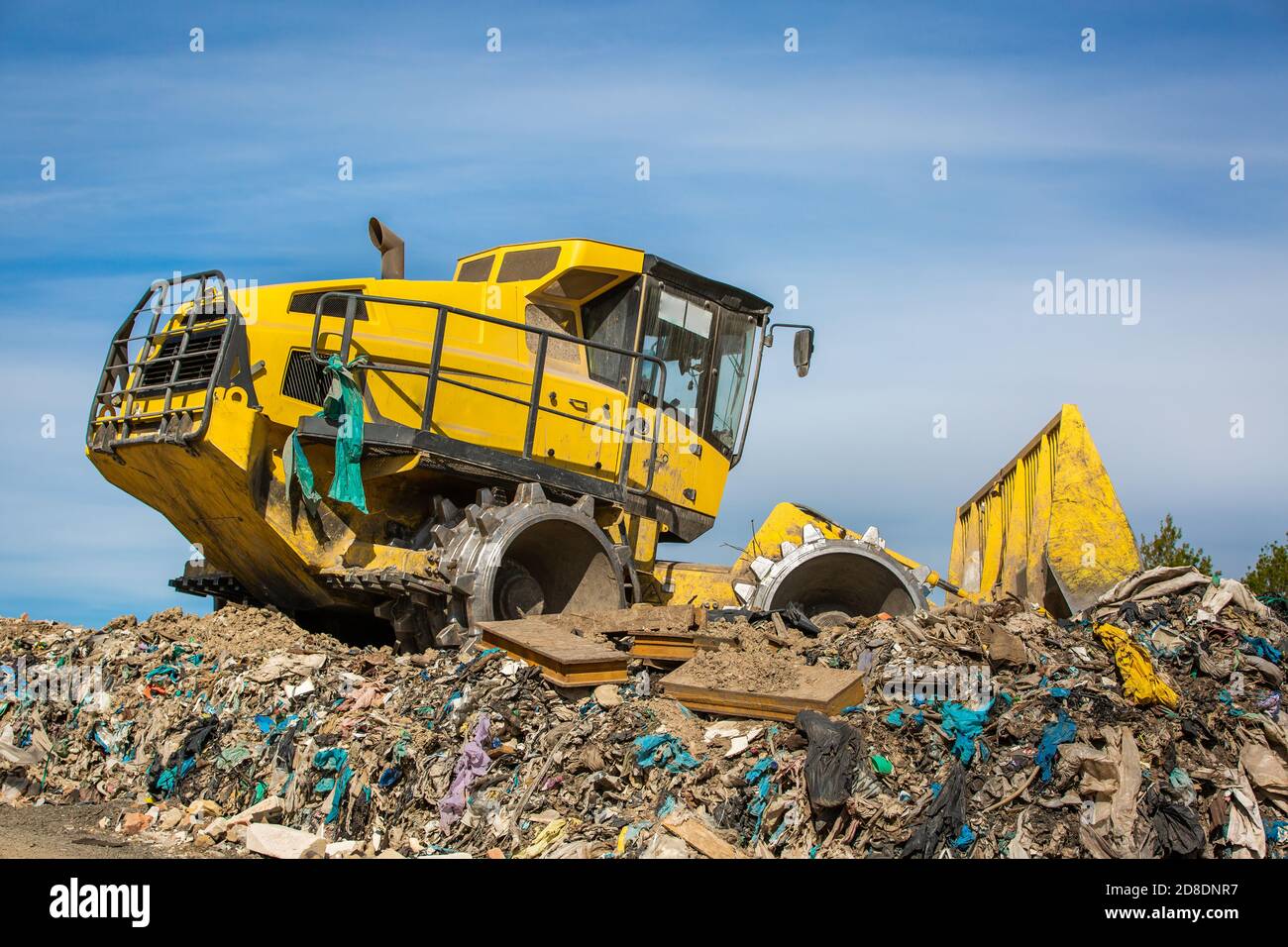 Huge bulldozer working at the huge landfill or garbage dump, pollution ...