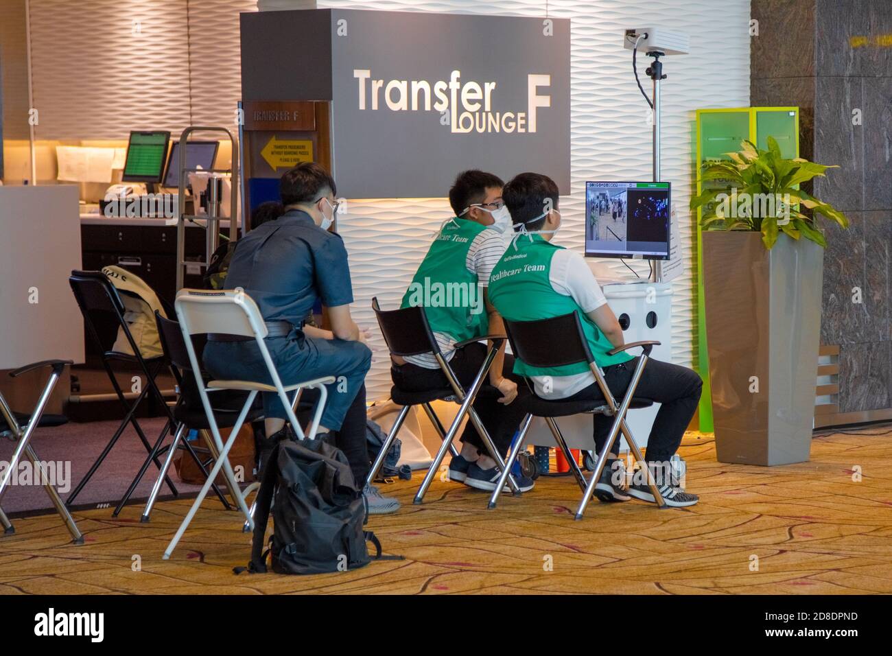 SINGAPORE - JULY 21. 2020: Changi airport staff sit behind a thermal ...