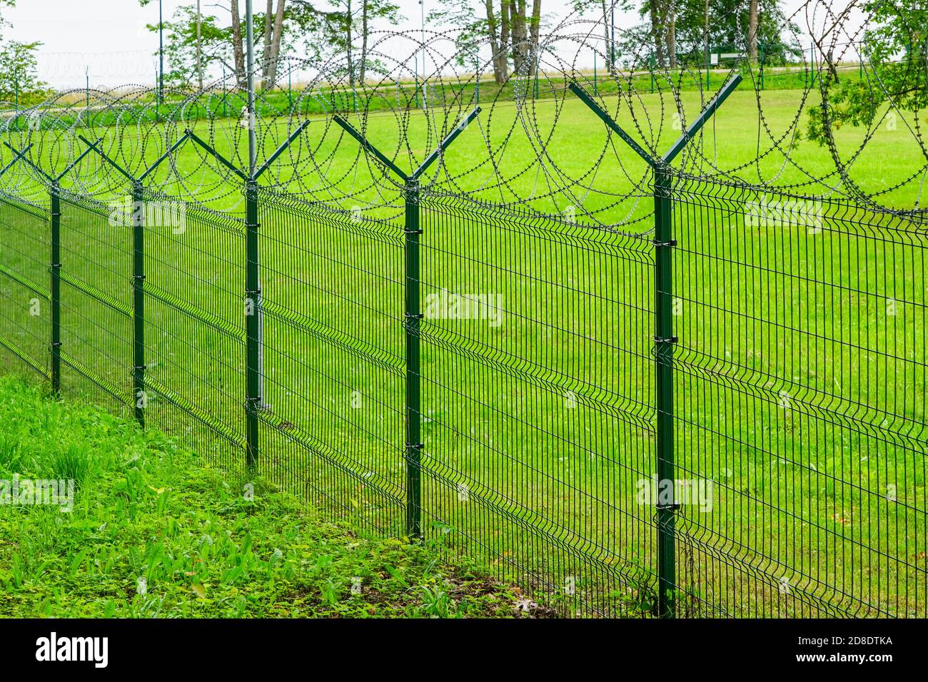 green metal fence with barbed wire around a military object Stock Photo ...