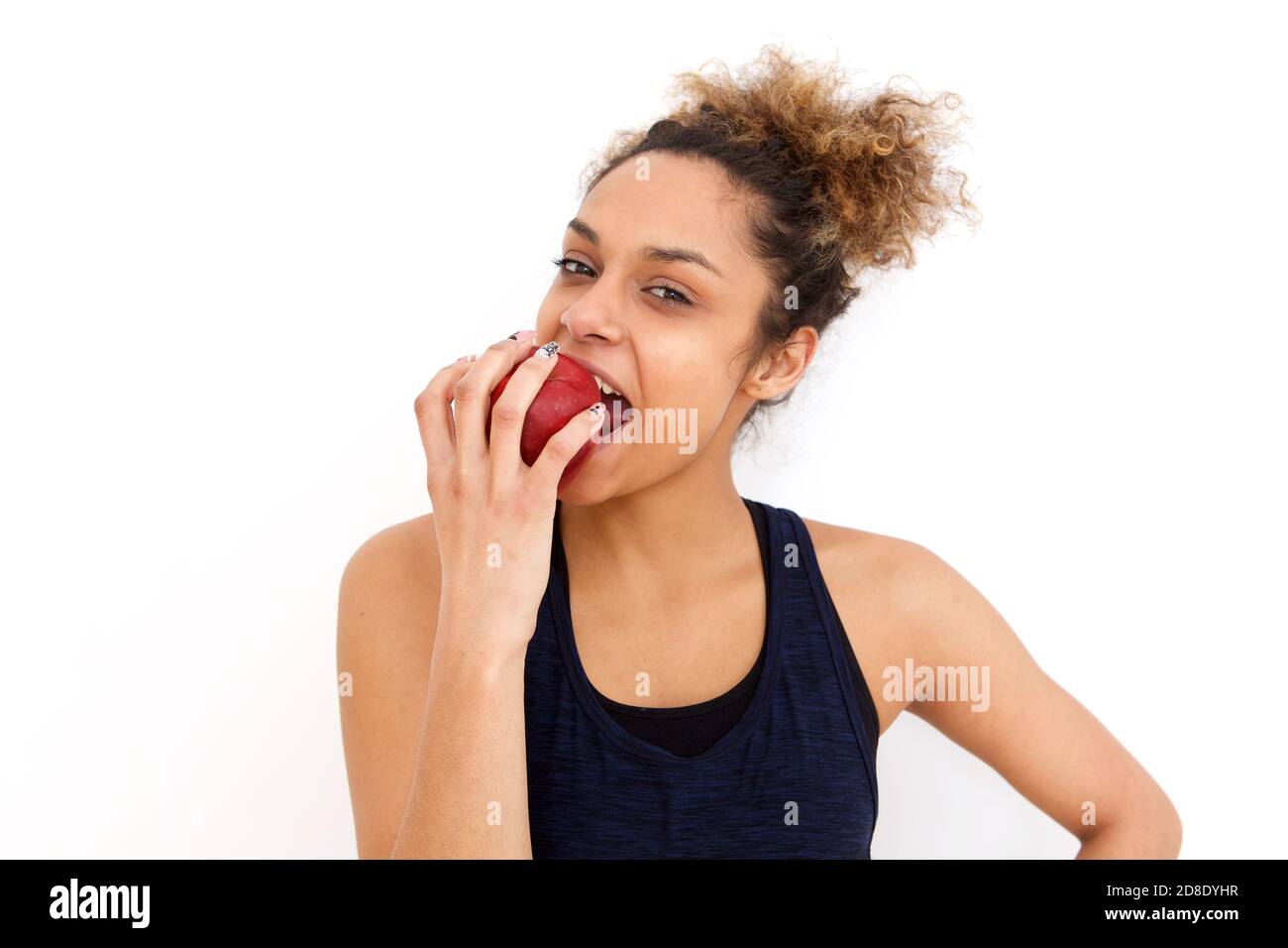 Portrait of beautiful african american girl eating apple against white ...