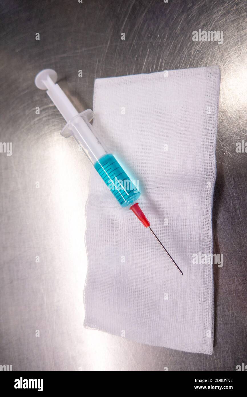 a syringe filled with blue liquid lies on a white compress Stock Photo ...