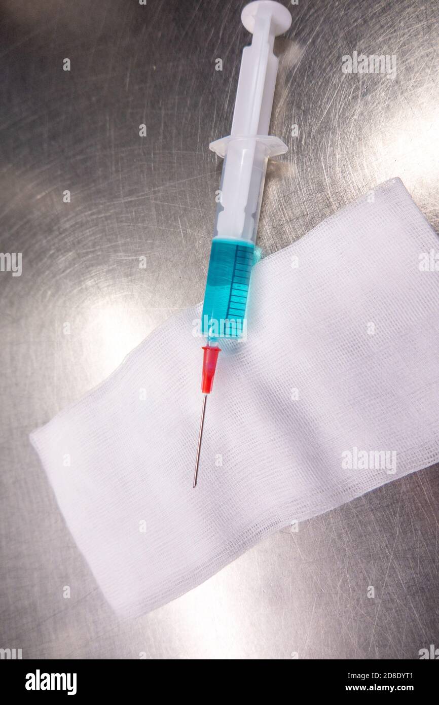 a syringe filled with blue liquid lies on a white compress Stock Photo ...