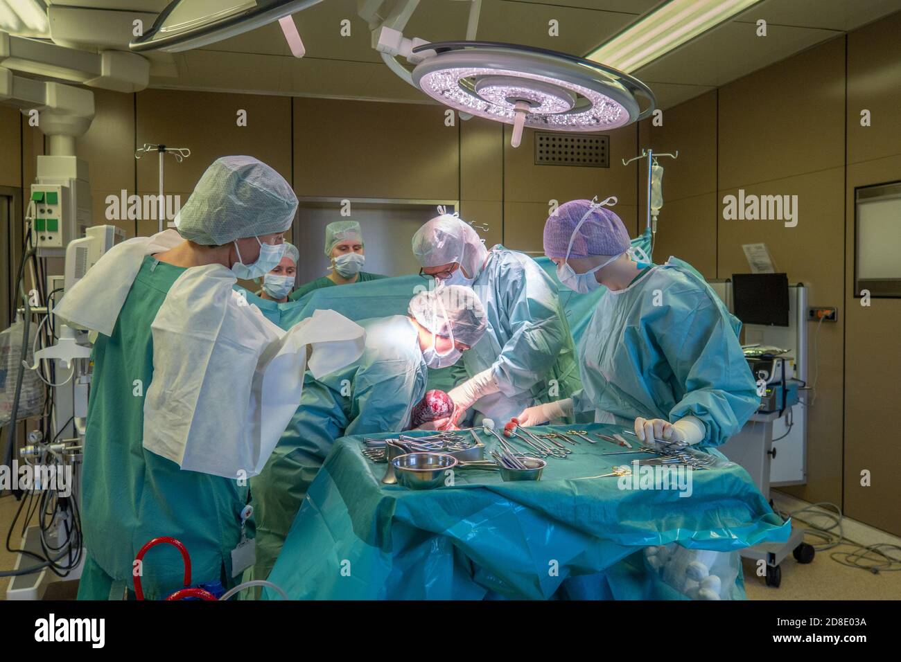 a team of gynecologists performs a caesarean section in an operating ...