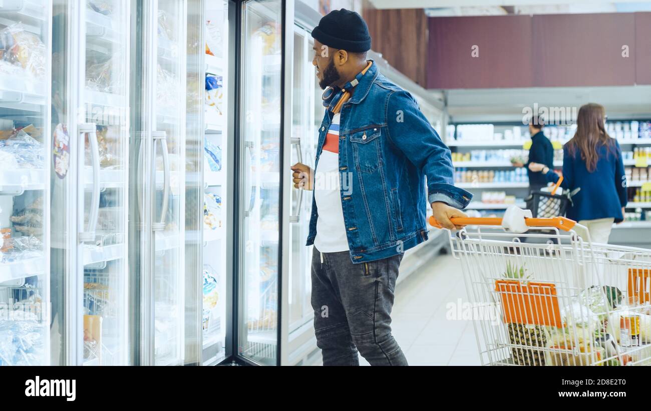 At the Supermarket: Happy Stylish Guy Pushes Shopping Cart and Chooses ...