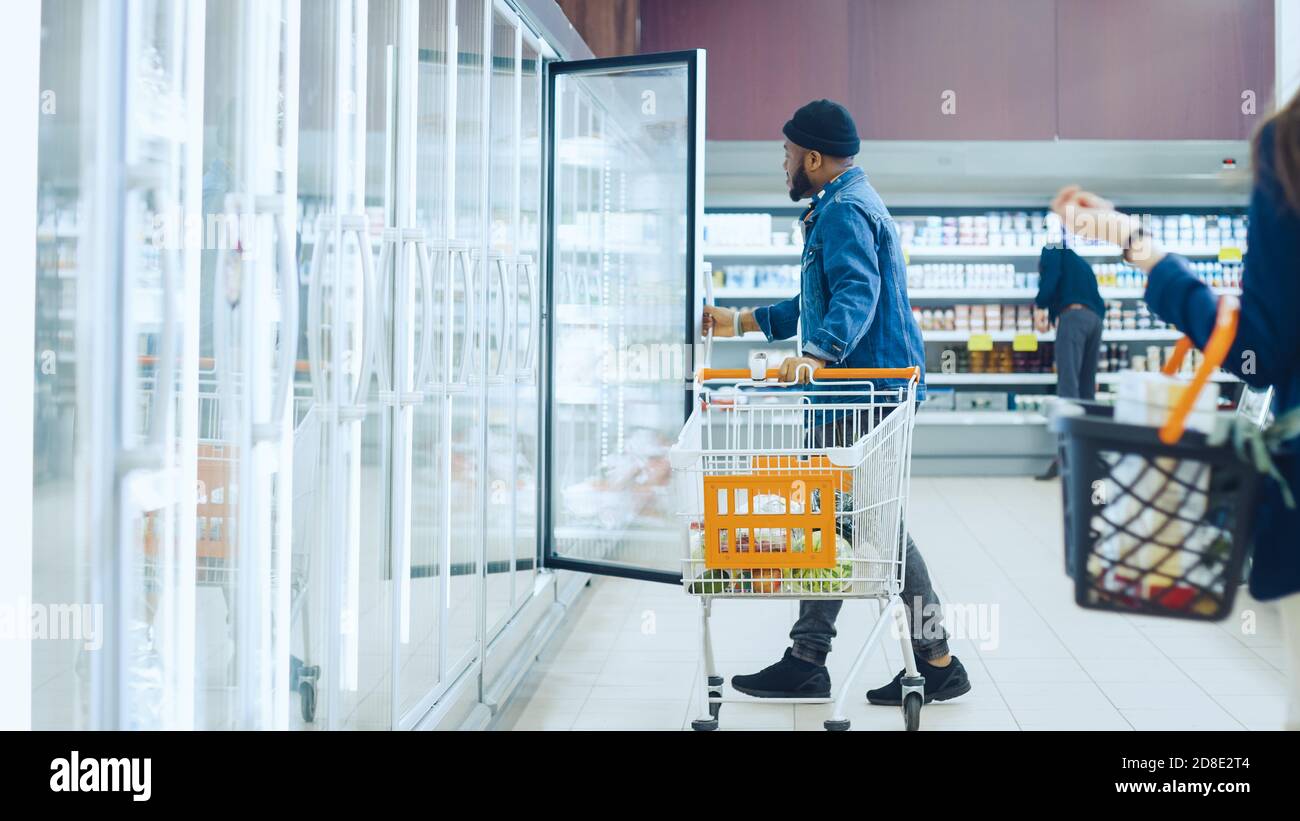 At the Supermarket: Happy Stylish Guy Pushes Shopping Cart and Chooses ...